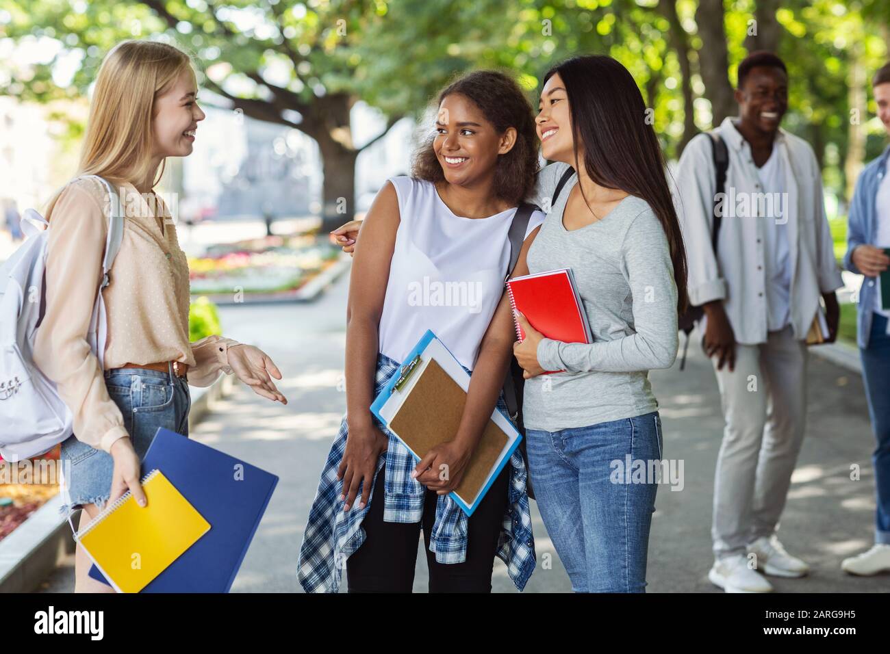 Young girls students discussing educational project, park background ...