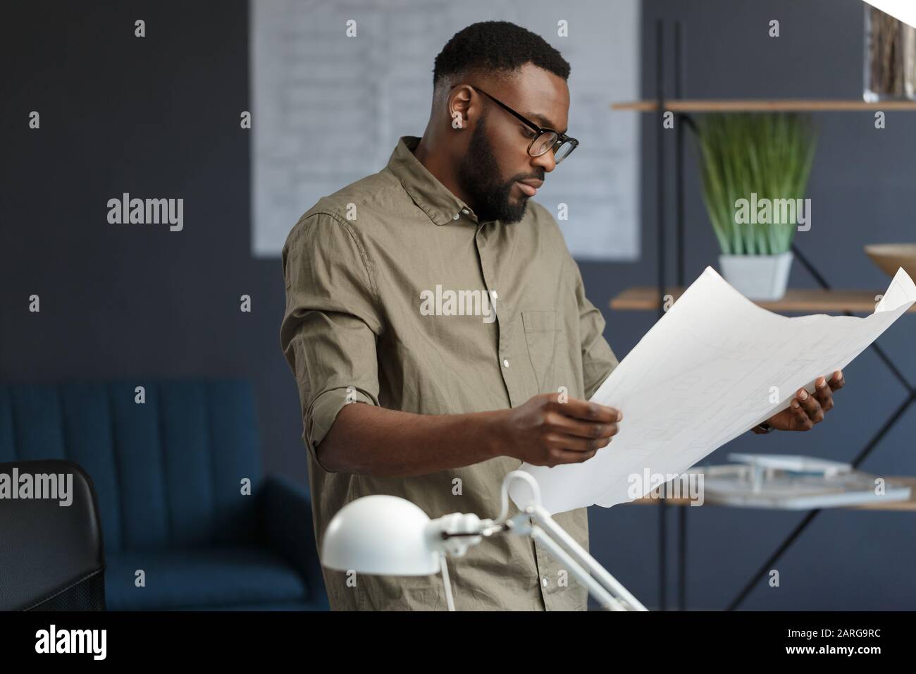 Afro-American architect working in office with blueprints.Engineer ...