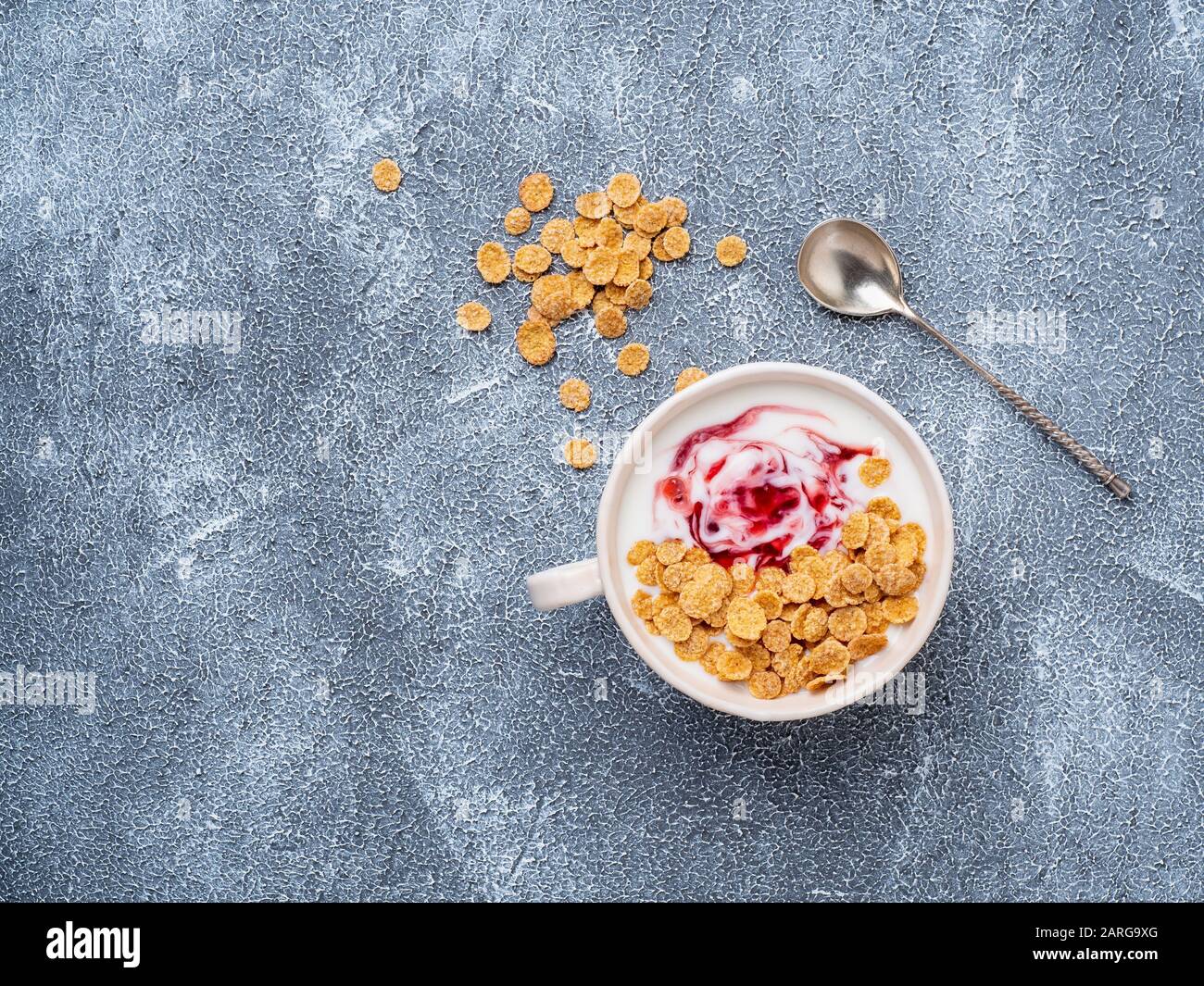 greek yogurt with jam and muesli in white bowl on grey blue concrete ...