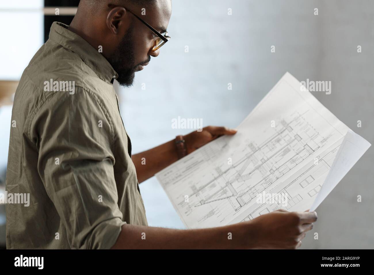 Afro-American architect working in office with blueprints.Engineer ...