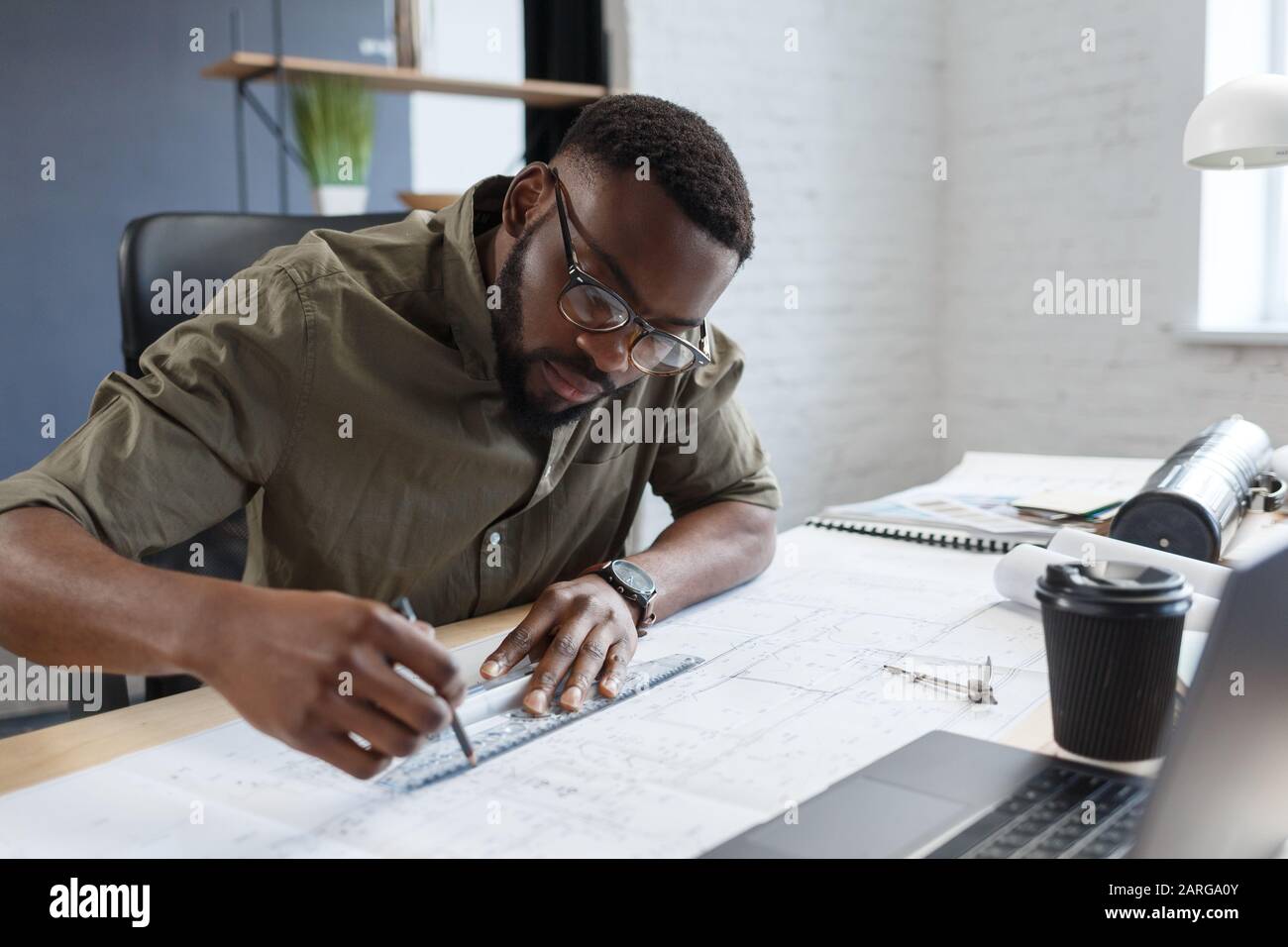 Afro-American architect working in office with blueprints.Engineer ...