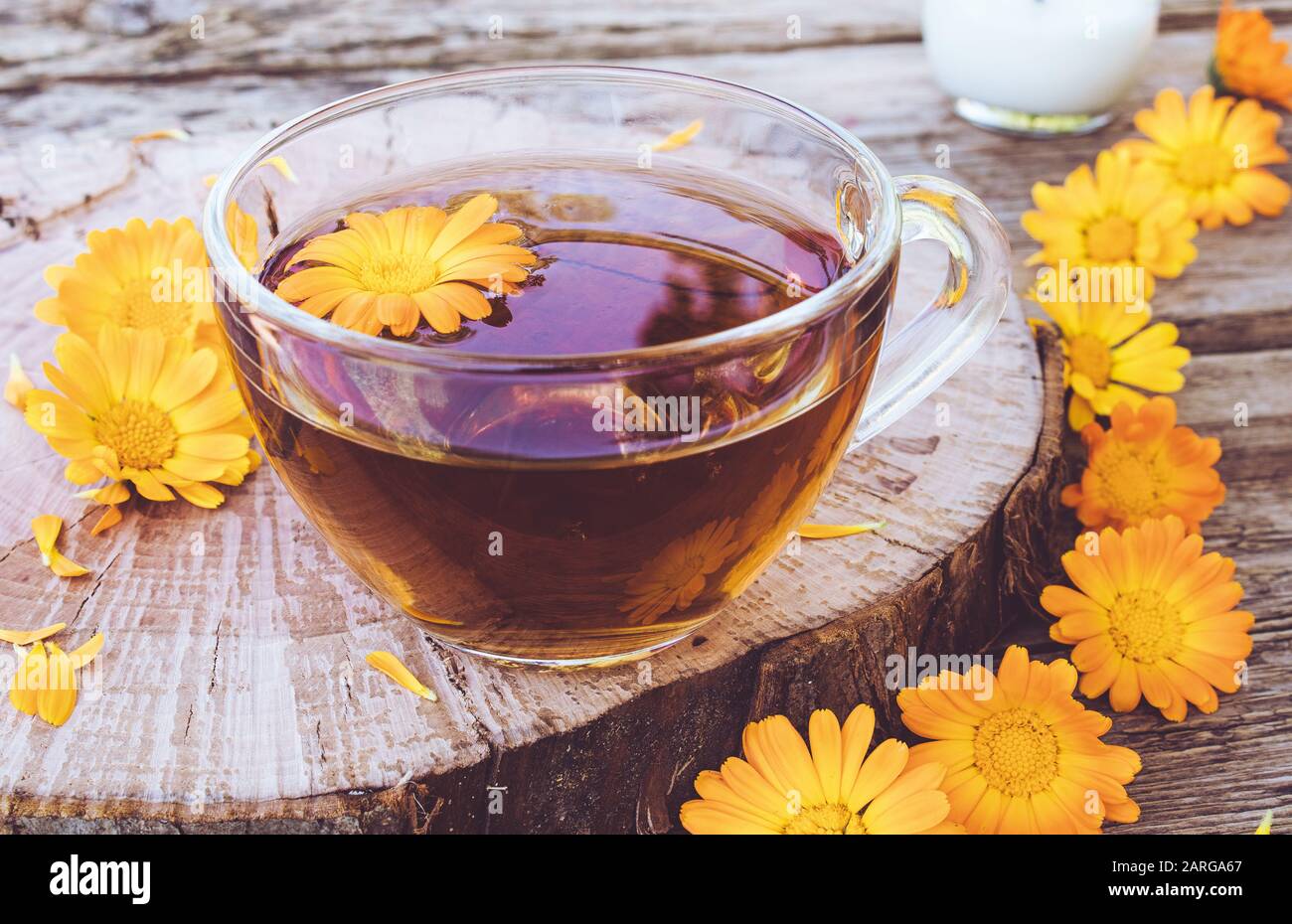 Herbal tea from calendula flowers in a transparent glass mug. Extract ...
