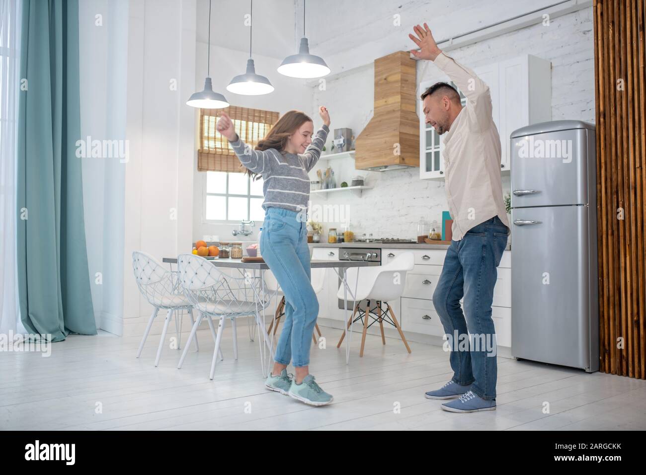 Smiling father with daughter dancing in the kitchen Stock Photo - Alamy