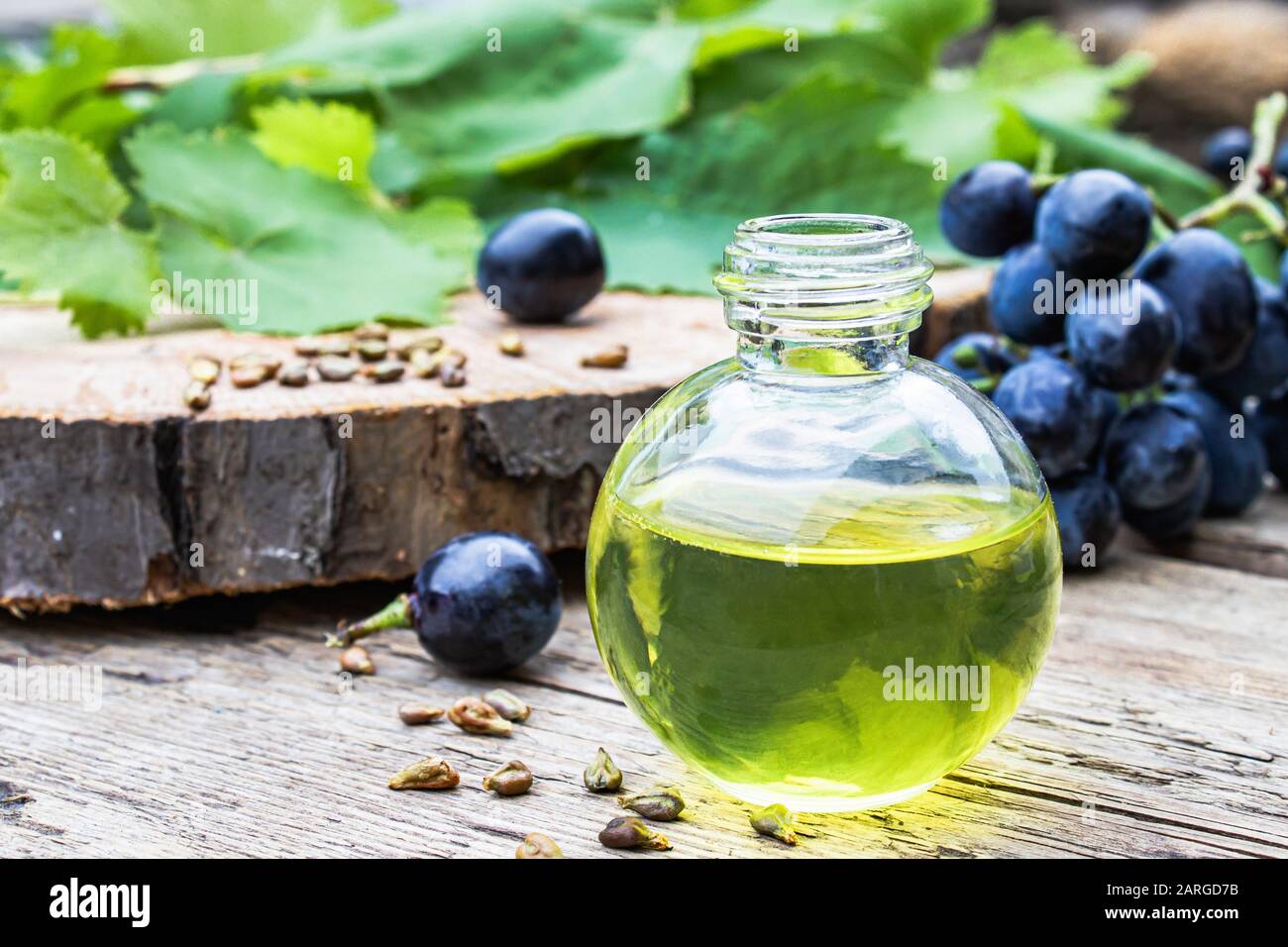 Grapes essential oil in a glass bottle and dice on old wooden boards ...