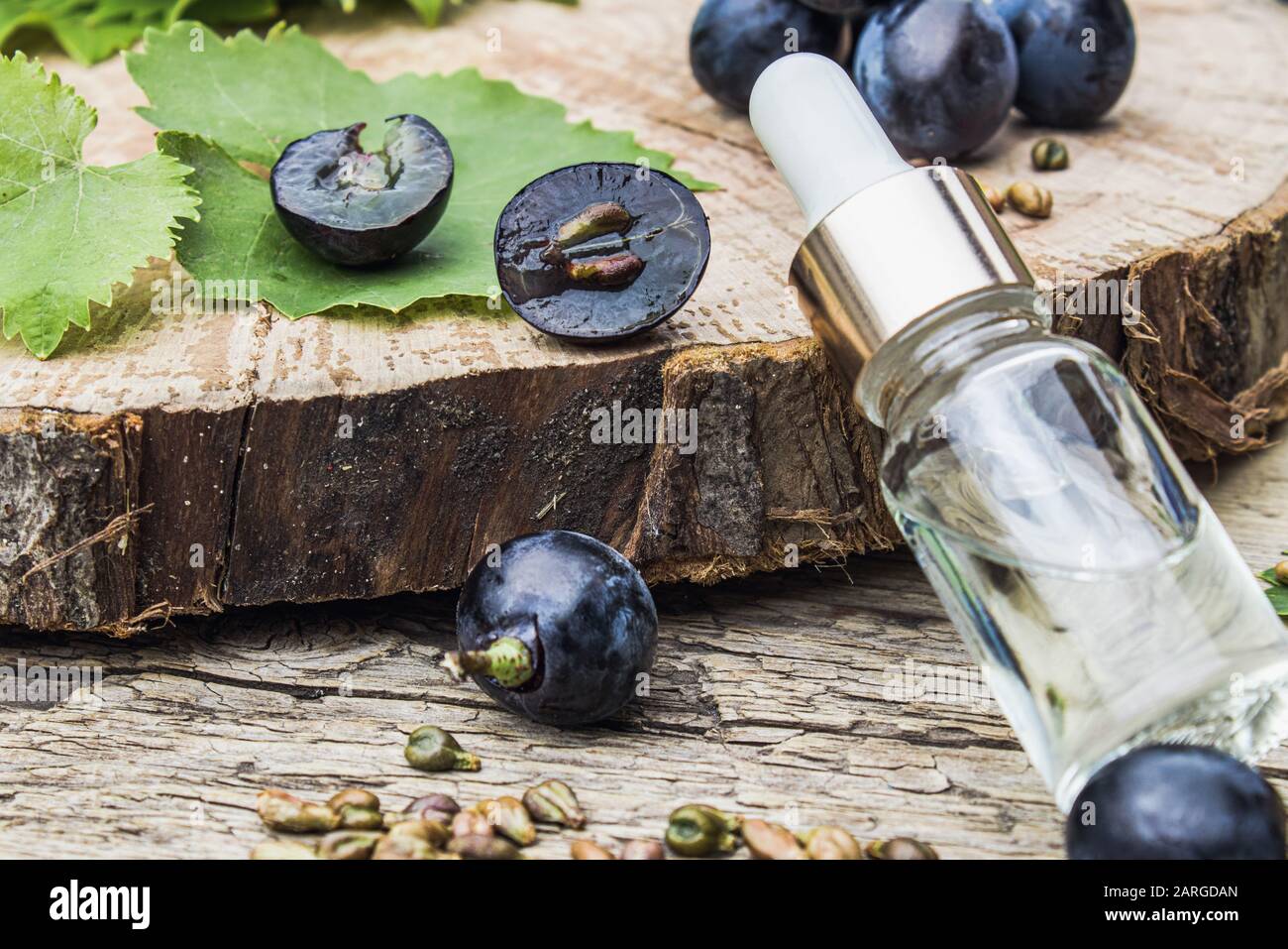 Grapes essential oil in a glass bottle and dice on old wooden boards ...