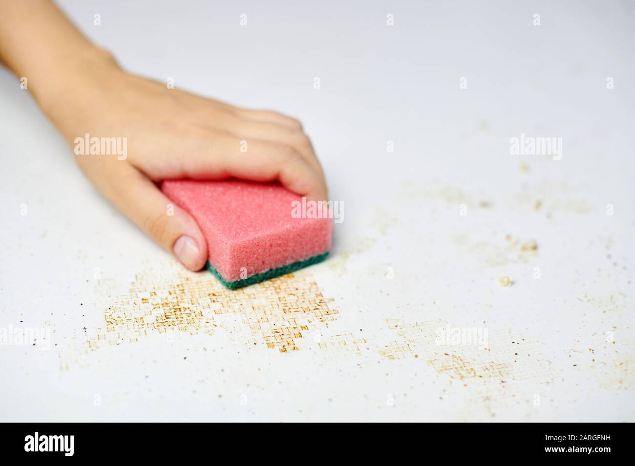 Cleaning kitchen table. Pink sponge in woman hand removes dirt, bread ...