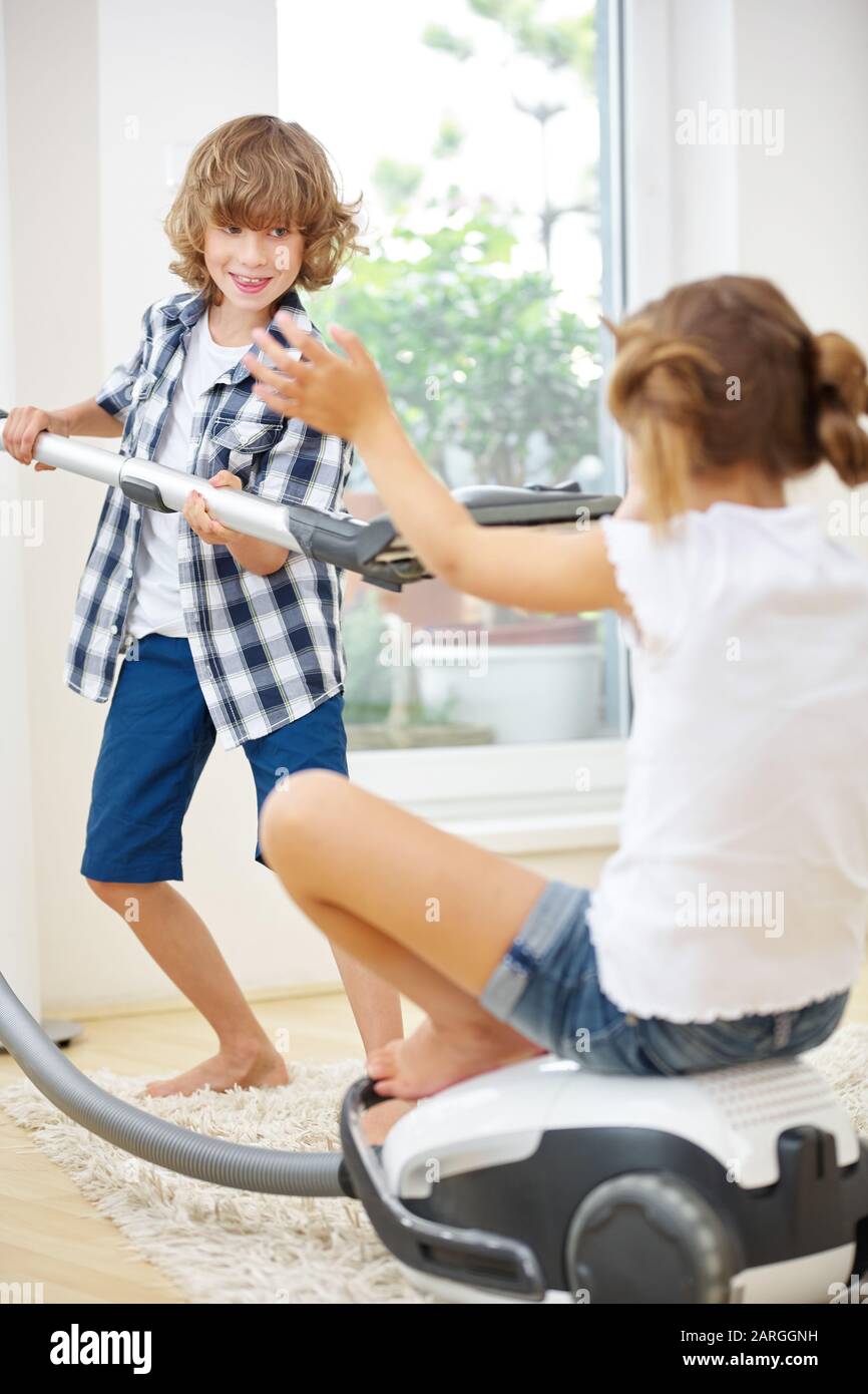 Two happy children play with a vacuum cleaner in the living room Stock ...