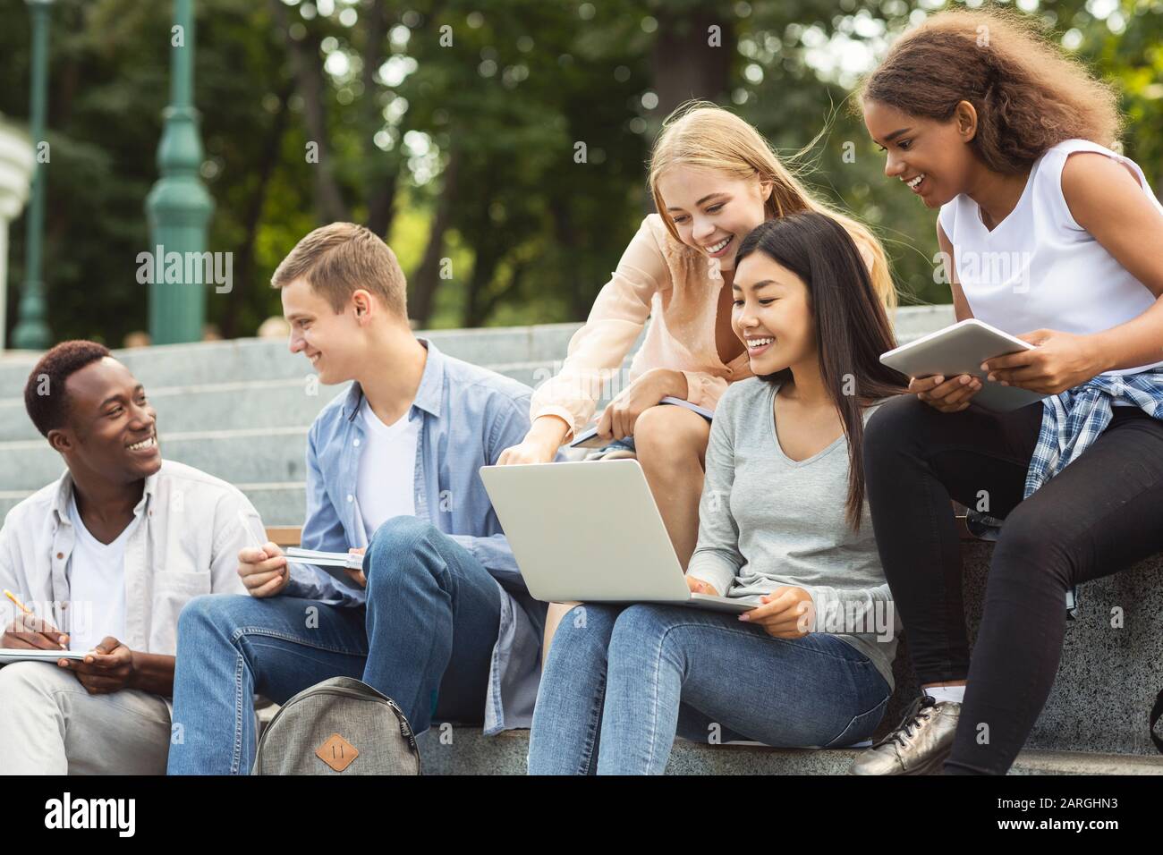 Group of positive students doing project together Stock Photo - Alamy