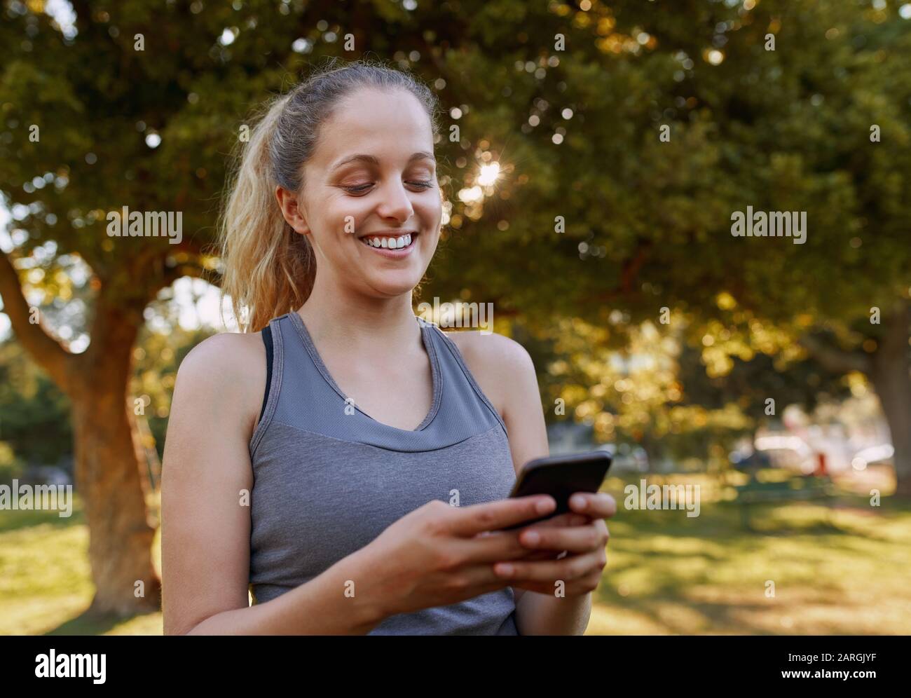 Portrait of a smiling beautiful blonde young woman texting message on ...