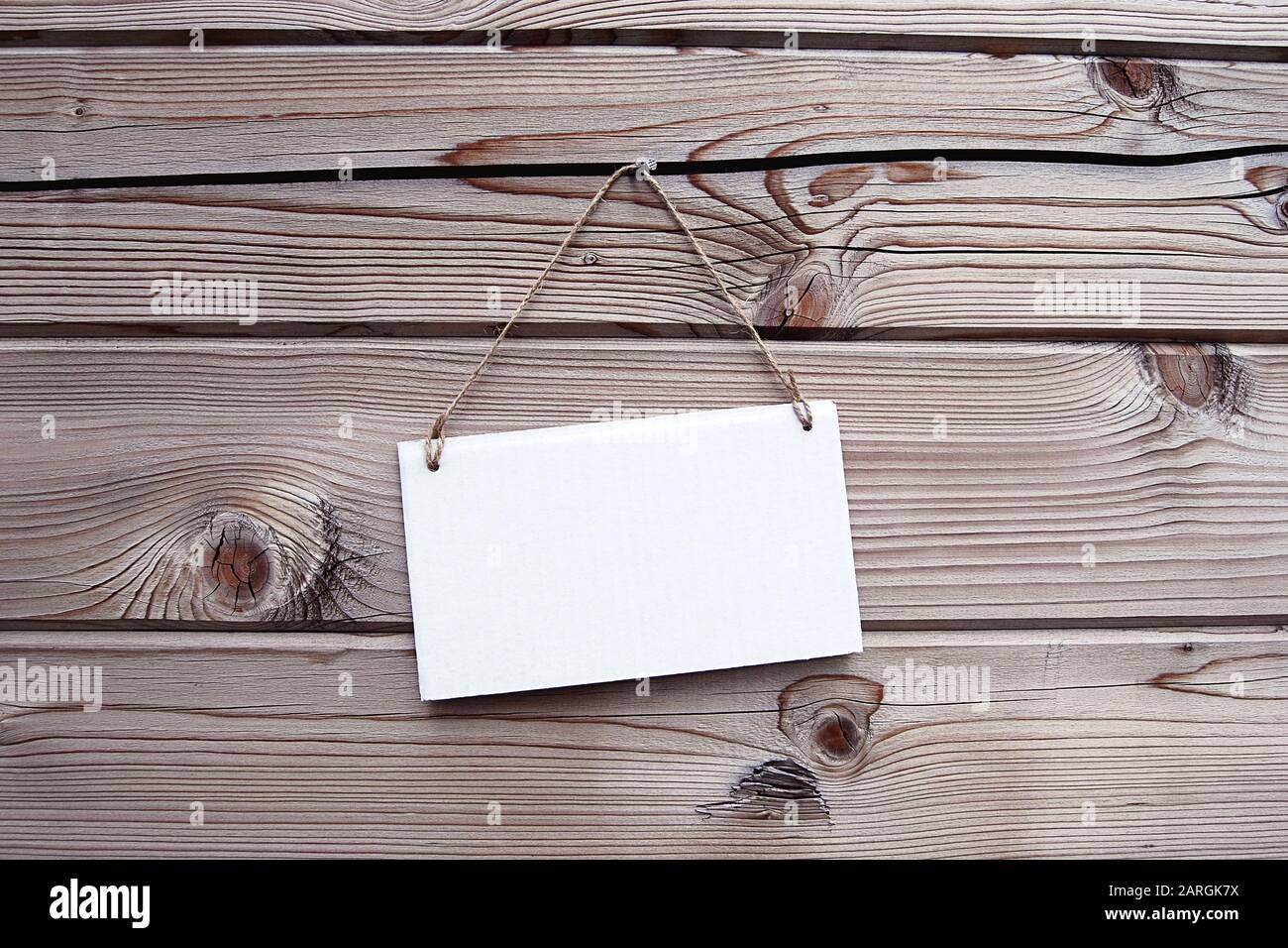 Natural wood backdrop, white nameplate notice hanging on rope. Mockup ...