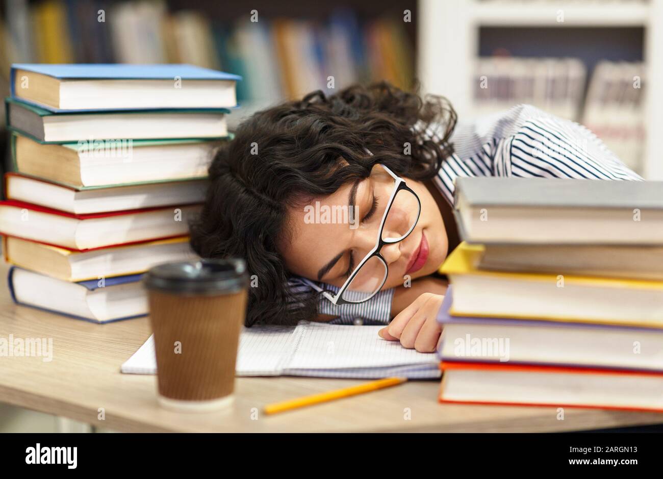 Tired woman napping on books stack in library Stock Photo - Alamy