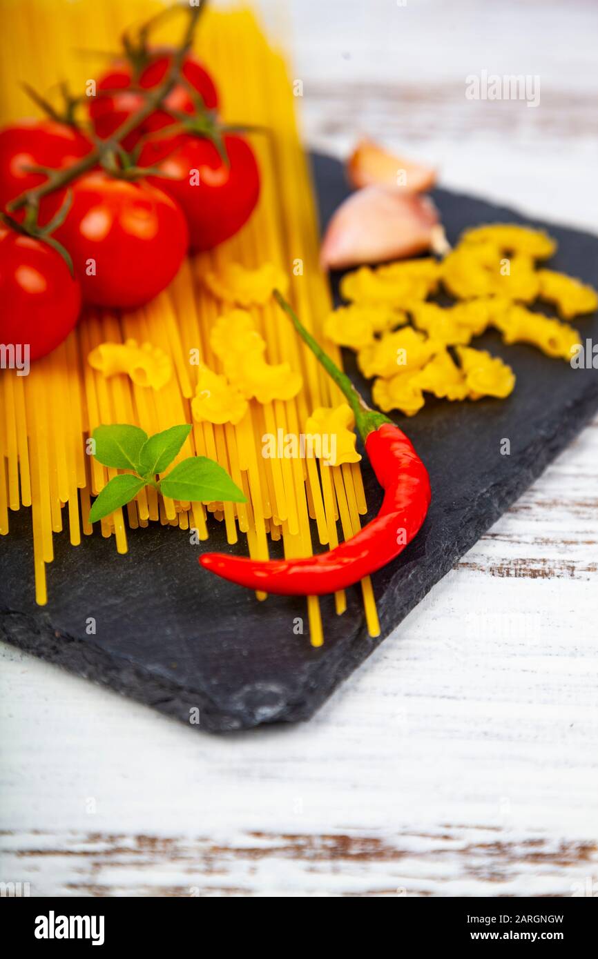 Spaghetti, tomatoes, chili peppers and spices on a wooden table. Still ...