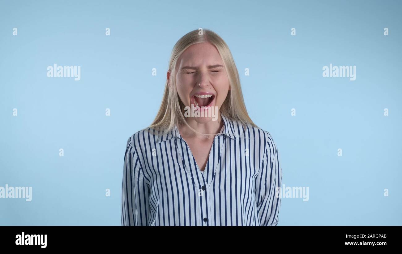 Pretty blonde girl shouting loudly. Blue background Stock Photo - Alamy
