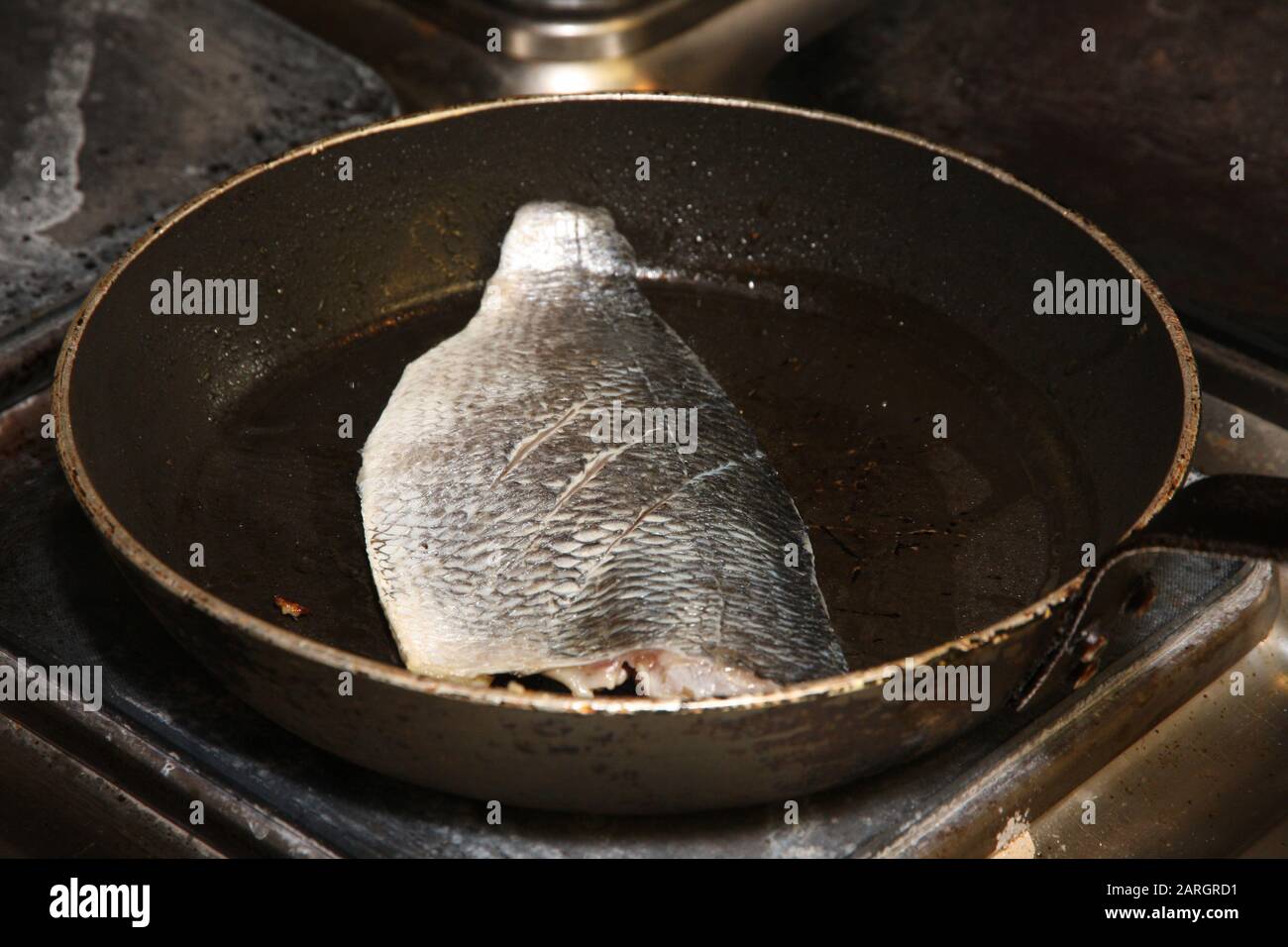 Sea bass frying in a pan Stock Photo - Alamy