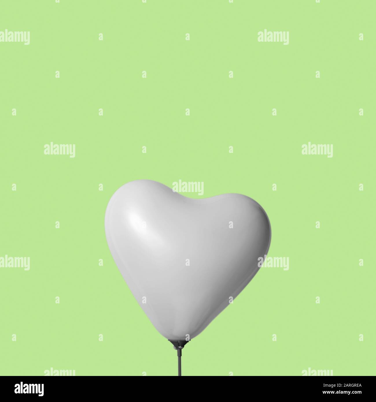 an inflated heart-shaped balloon in black and white against a green ...