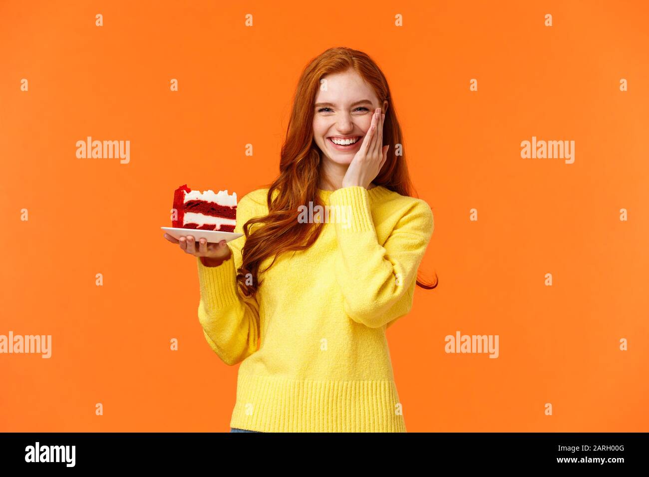 Happy lovely caucasian redhead female holding tasty cake with cream ...