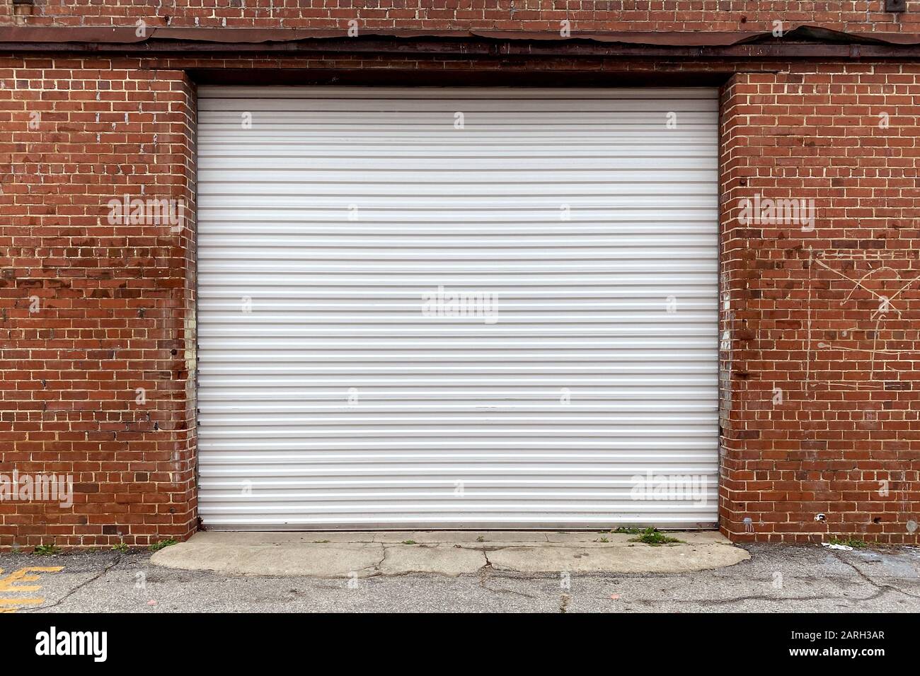 a brick wall warehouse with receiving door in an alley Stock Photo - Alamy