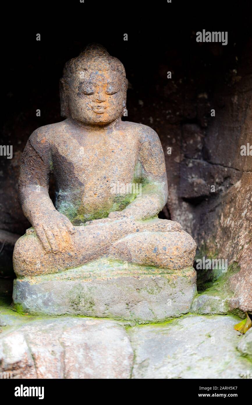 A stone statue of a sitting buddha with stone background Stock Photo ...