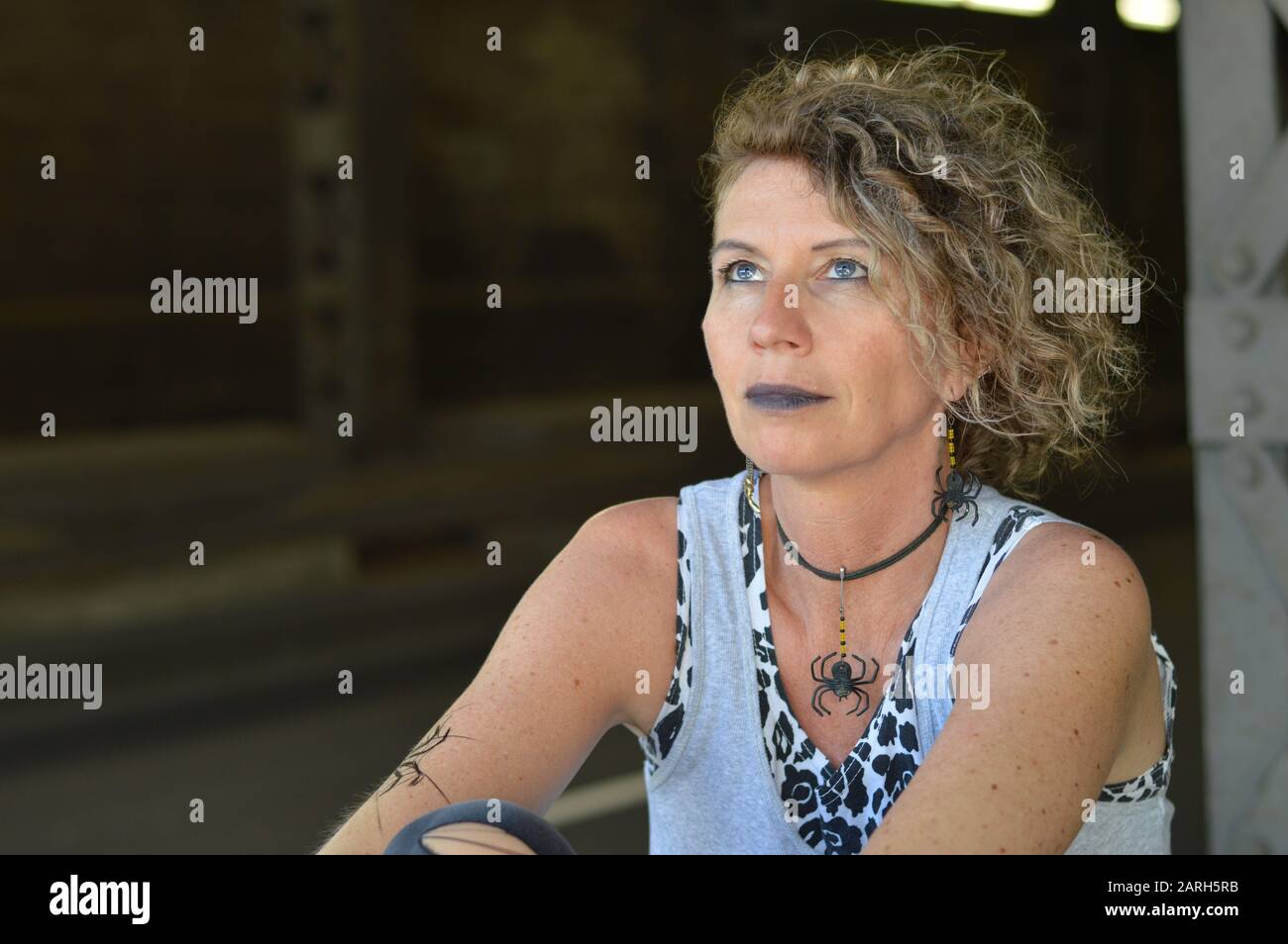 a mature punk woman is sitting in an underground and looking hopefully ...