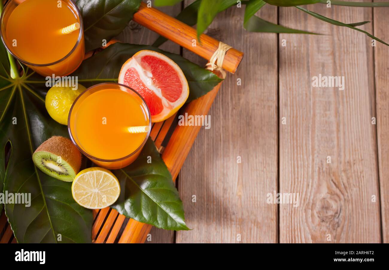 Two glasses of tropical exotic multifruit juice on a palm leaves. Top ...