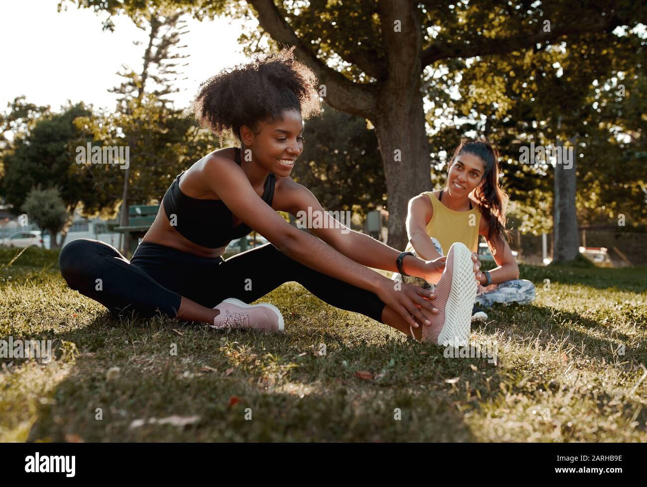 Smiling two diverse sporty fit young female friends stretching their ...