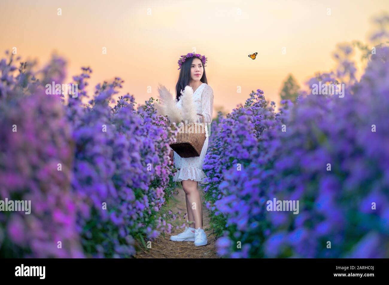 A woman watching flowers in a flower field with butterflies in the ...