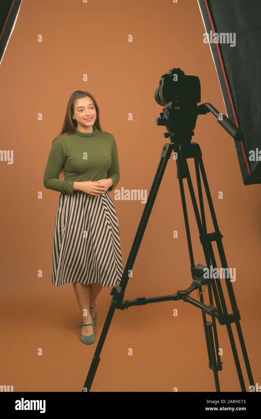 Young beautiful Indian woman vlogging against brown background Stock ...
