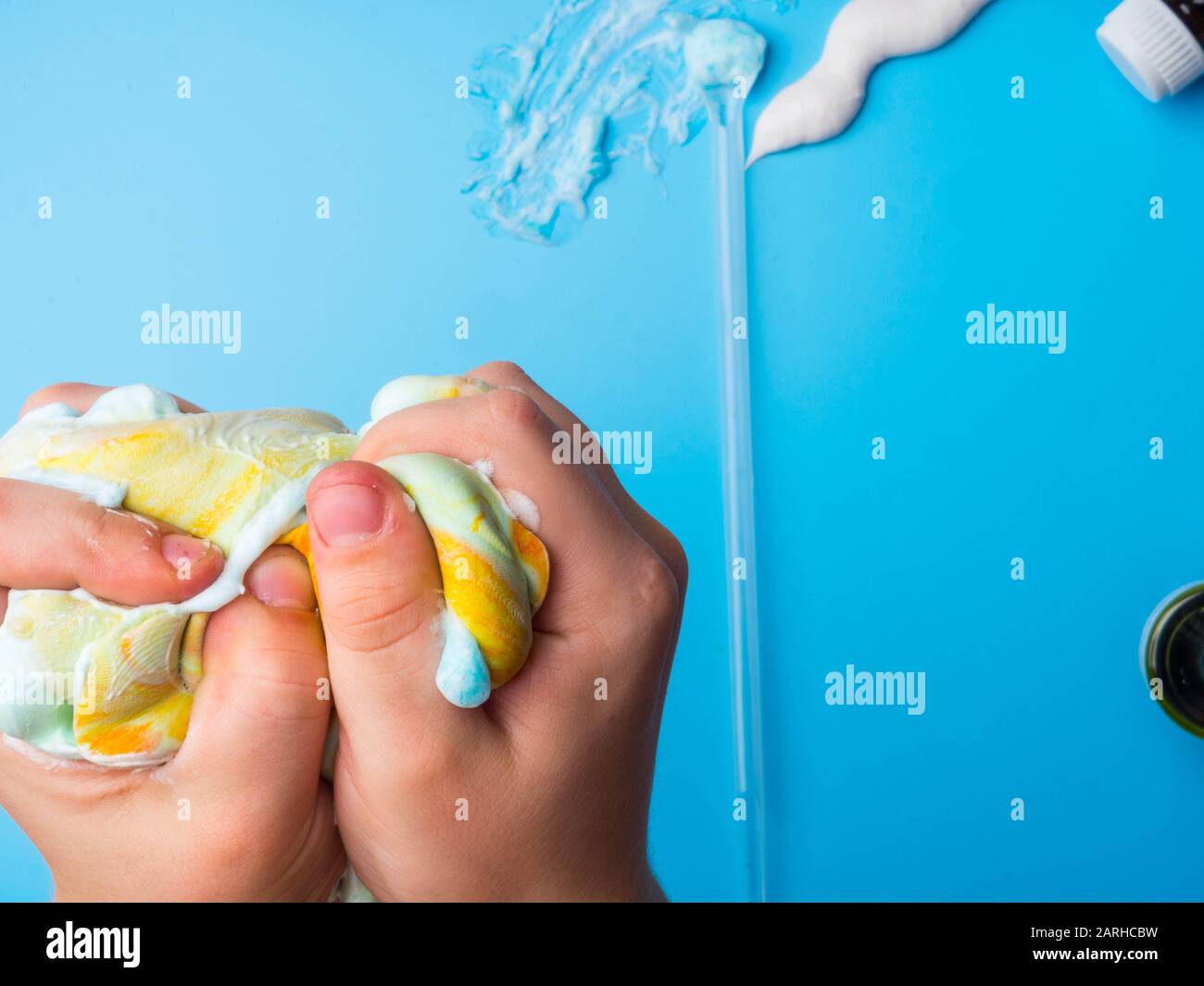 On blue surface slime with orange paint. Children hands holding slime ...