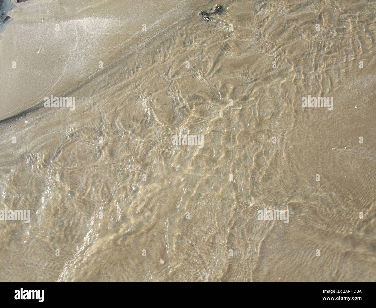 Water flowing over sand forming pattern Stock Photo - Alamy