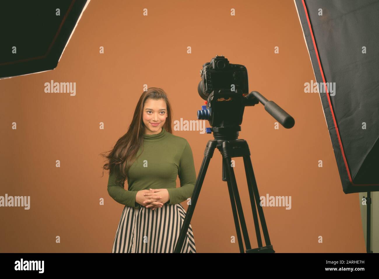 Young beautiful Indian woman vlogging against brown background Stock ...