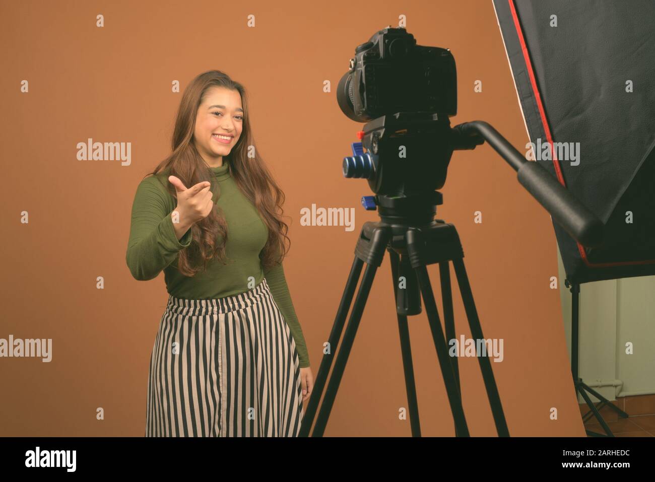 Young beautiful Indian woman vlogging against brown background Stock ...