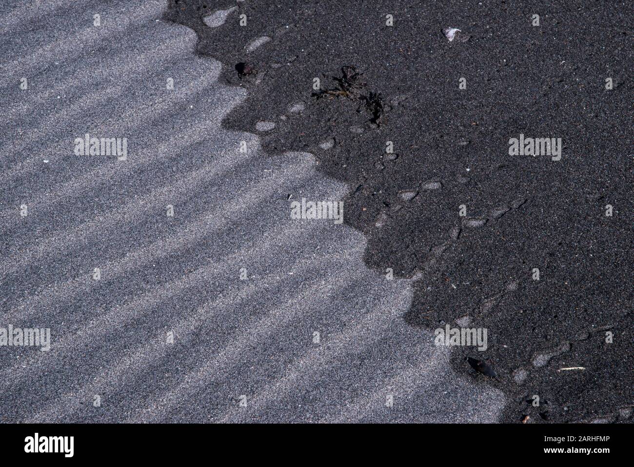 Detail of water flowing over black sand at Oakura Beach, New Zealand ...