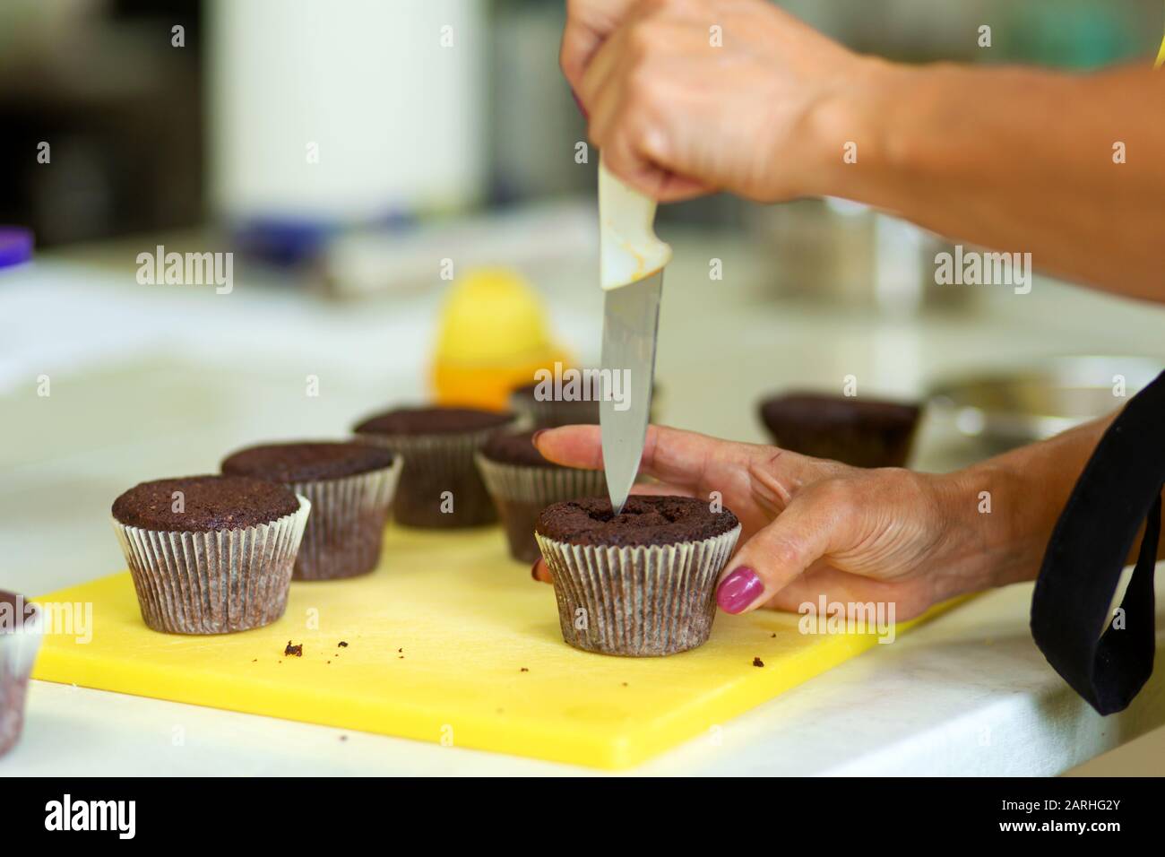 The process of making chocolate cupcakes with sweet cream. Creation of cakes by professional ...