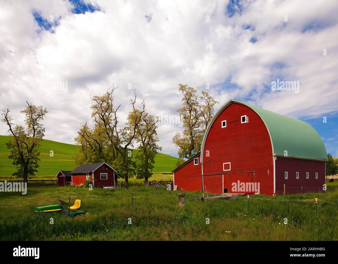 Big, red barn near rolling wheat fields on a partly sunny day in the ...