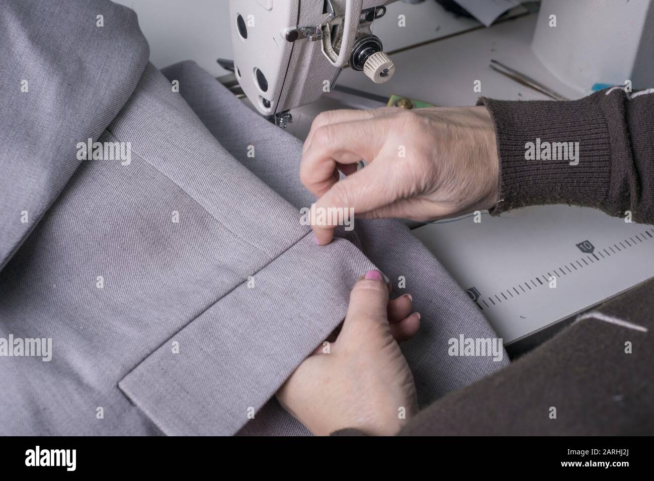 a couturier master, against the background of a sewing machine, sews ...