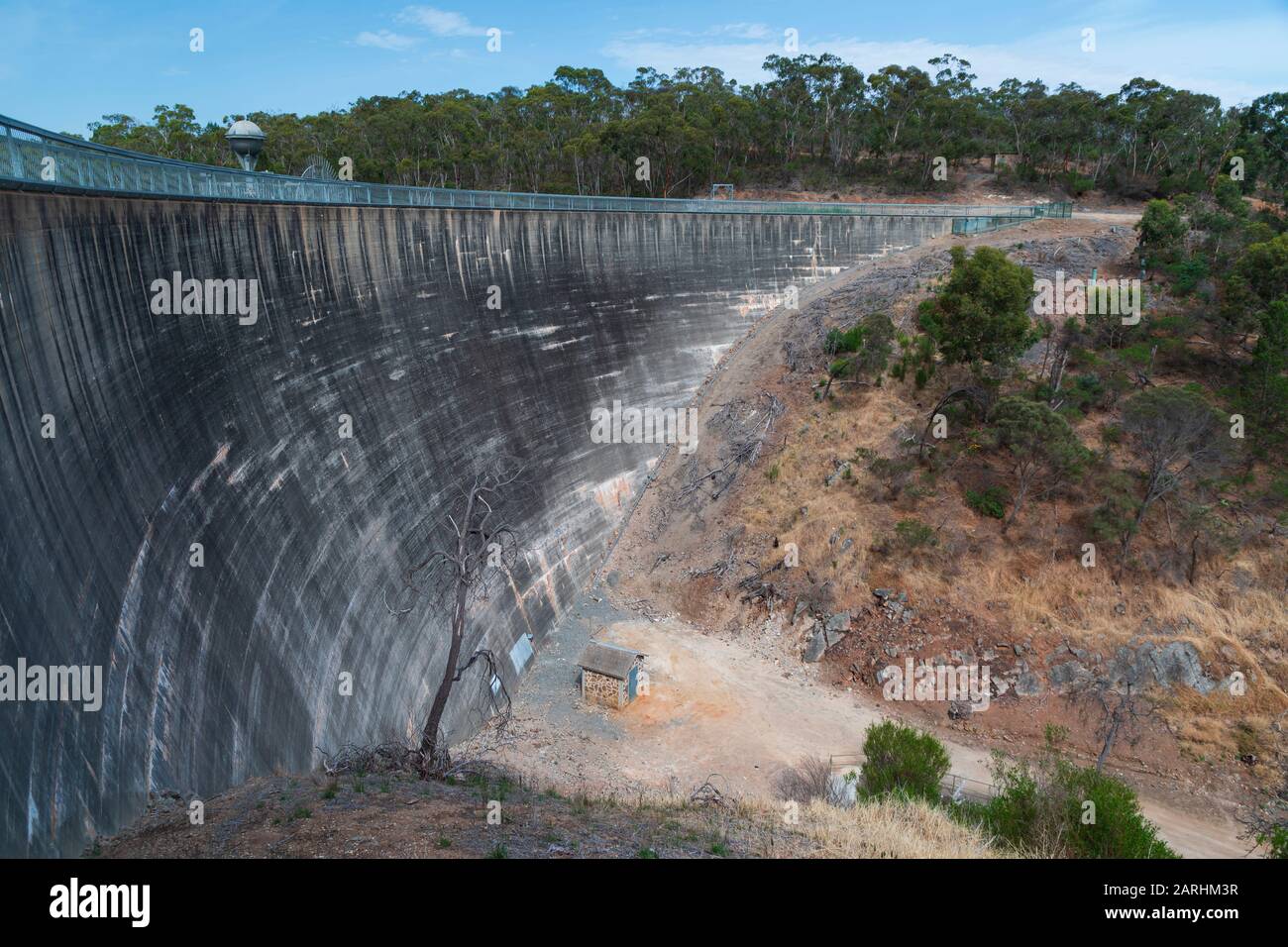 A large black reservoir concrete wall with handrails and a small ...