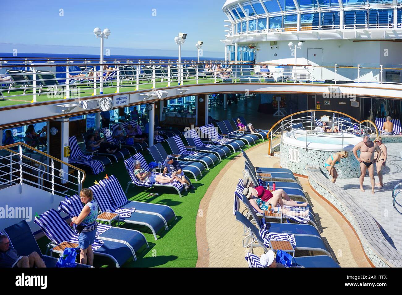 Cruise passengers enjoy sun and pool on deck of luxurious Cruise ship ...