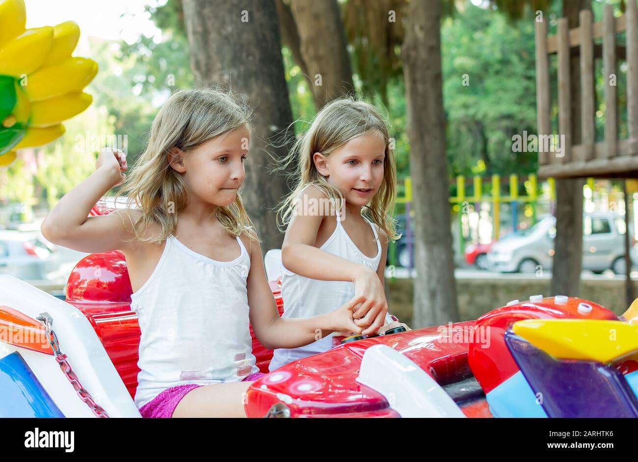 Two tween girls riding on colorful amusement in playground in funpark ...
