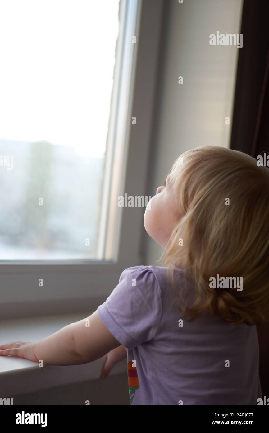 A little girl standing in front of a window Stock Photo - Alamy