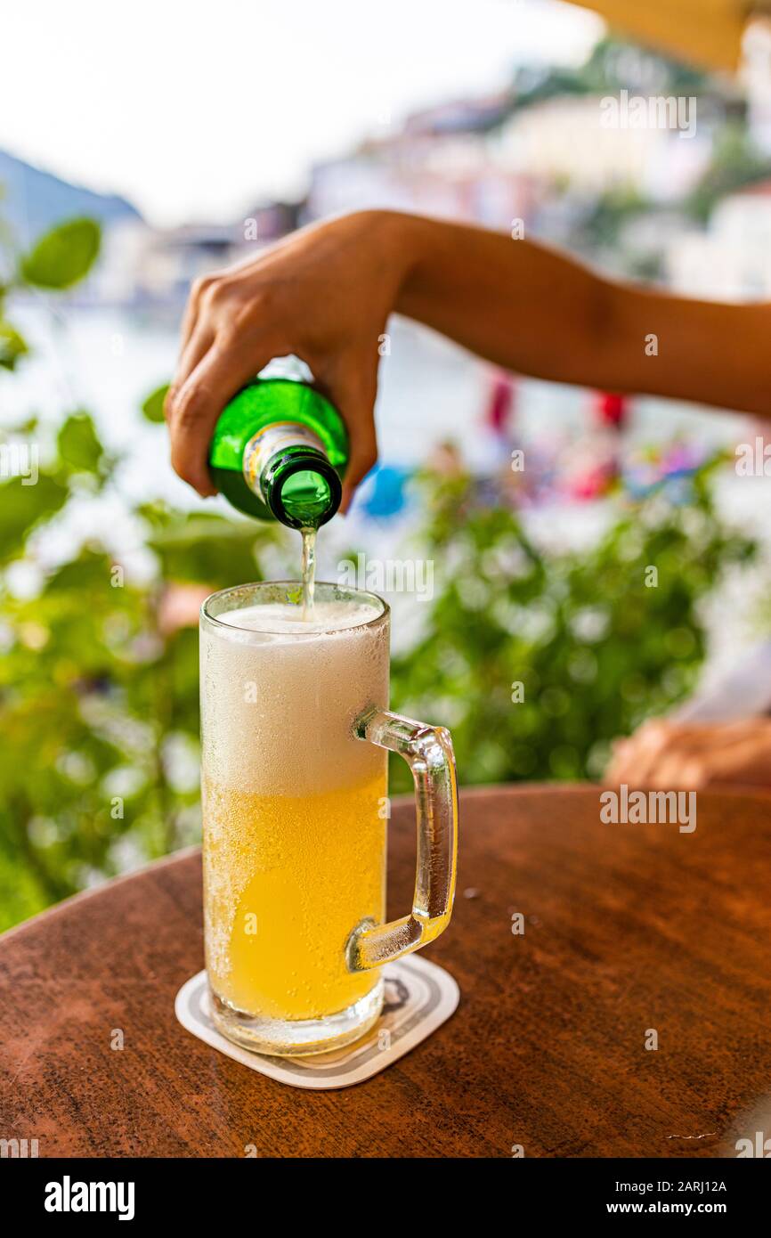 Hand filling a glass of beer on a terrace Stock Photo - Alamy