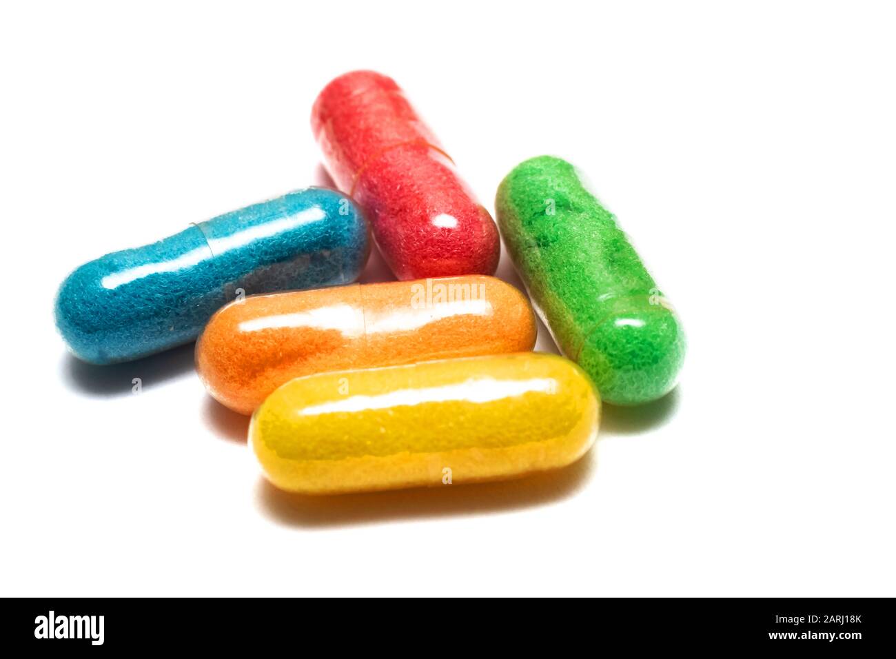 Multi-colored capsules vitamins close up isolated on a white background ...