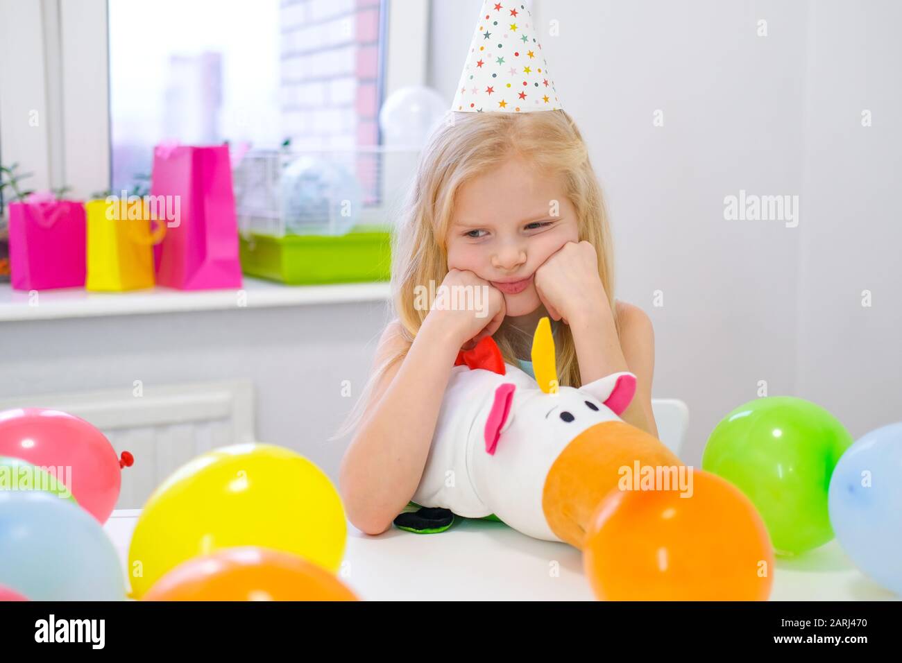 Unhappy blonde caucasian girl with boring face near birthday rainbow ...