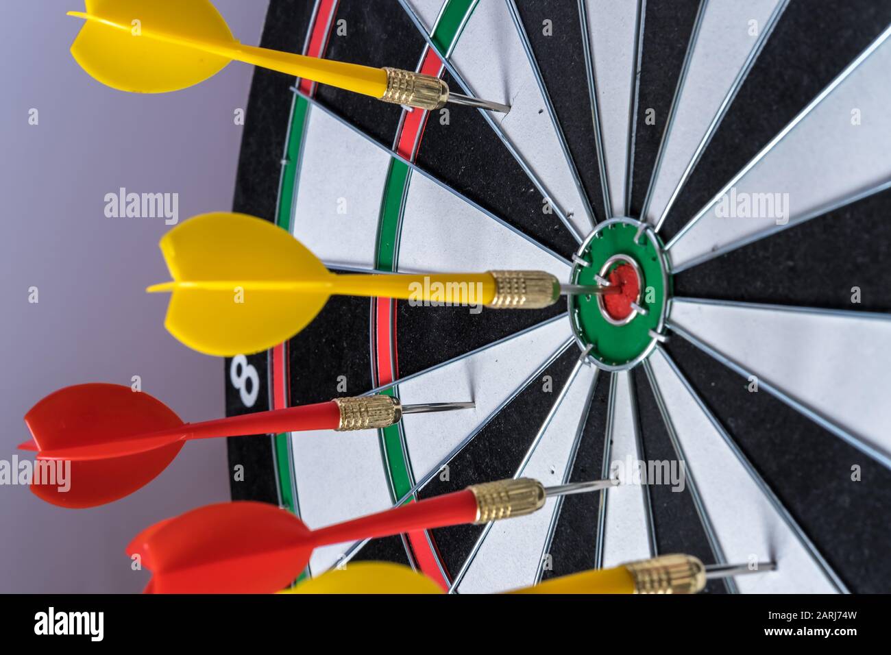 Red and yellow dart arrows hitting in the target center of dartboard ...