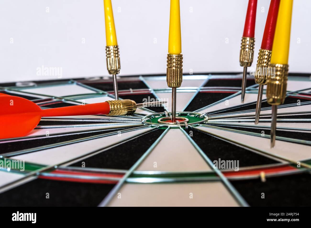 Red and yellow dart arrows hitting in the target center of dartboard ...