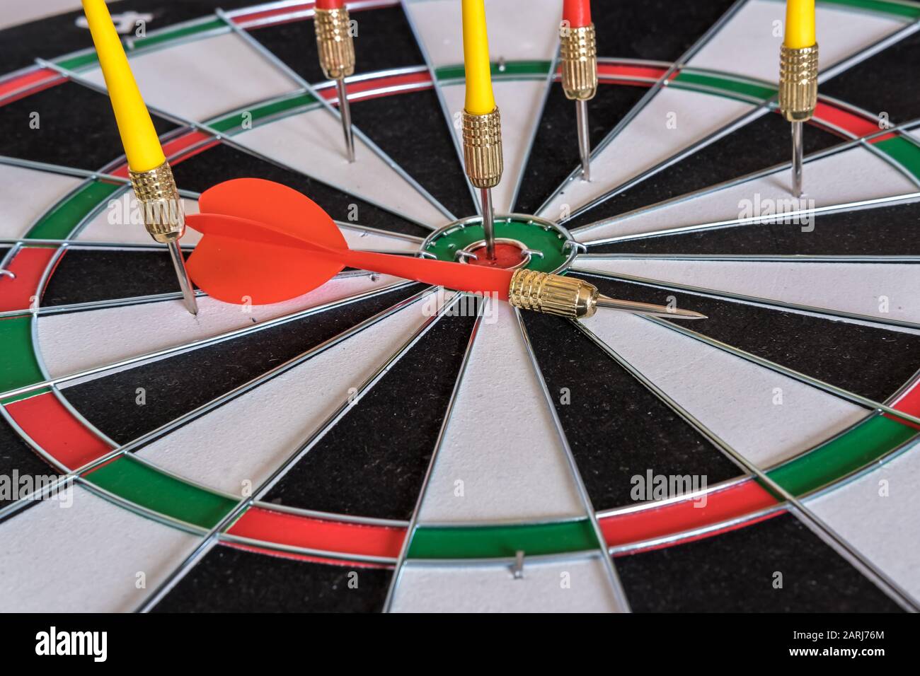Red and yellow dart arrows hitting in the target center of dartboard ...
