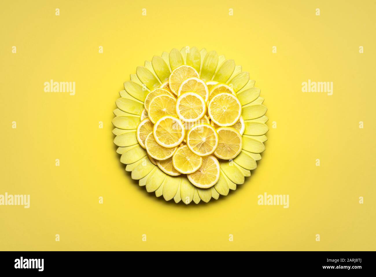 Slices of lemons on a yellow flower-shaped dish on yellow background ...