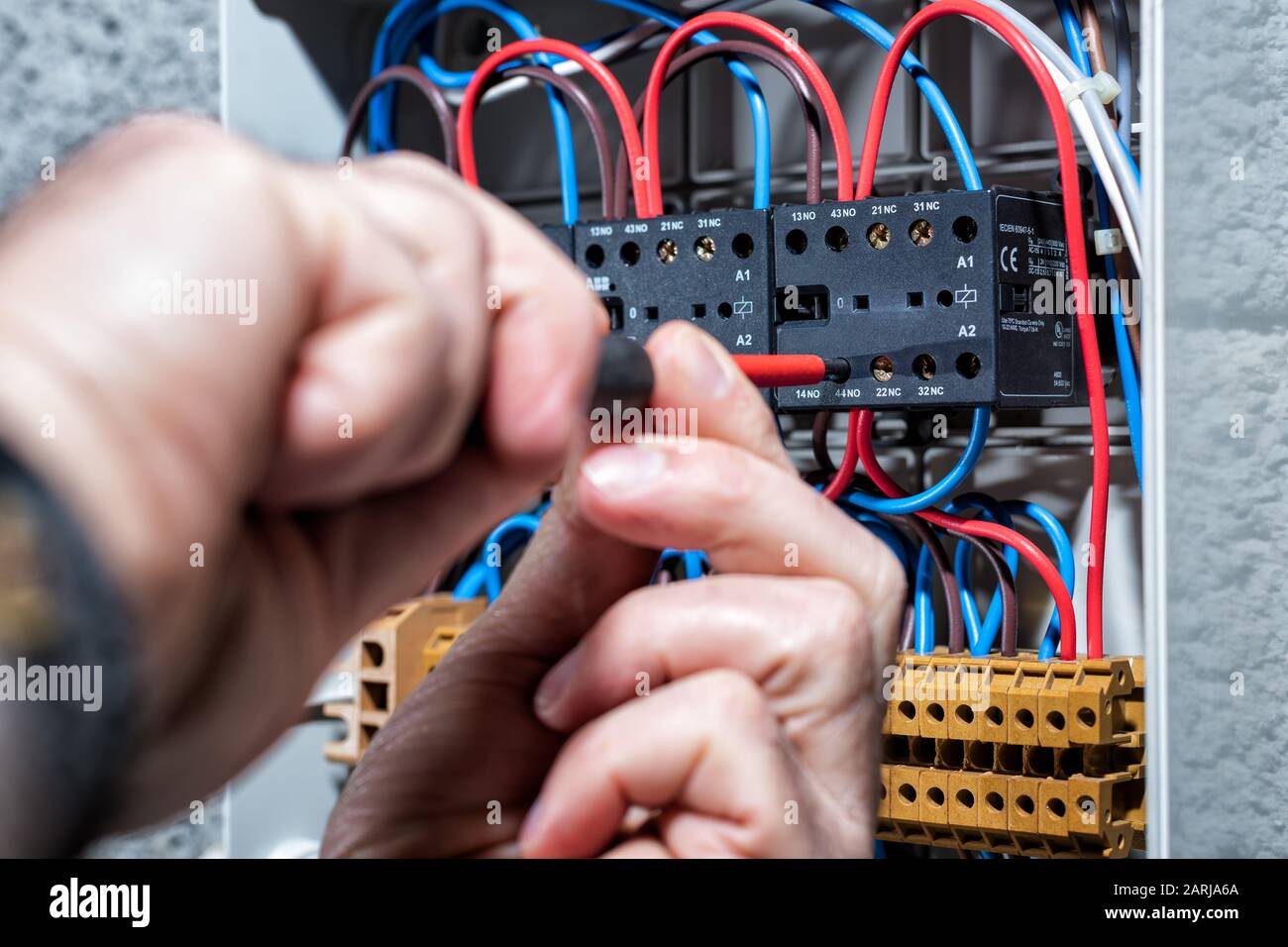 Electrician with screwdriver fixes the cable in a residential ...