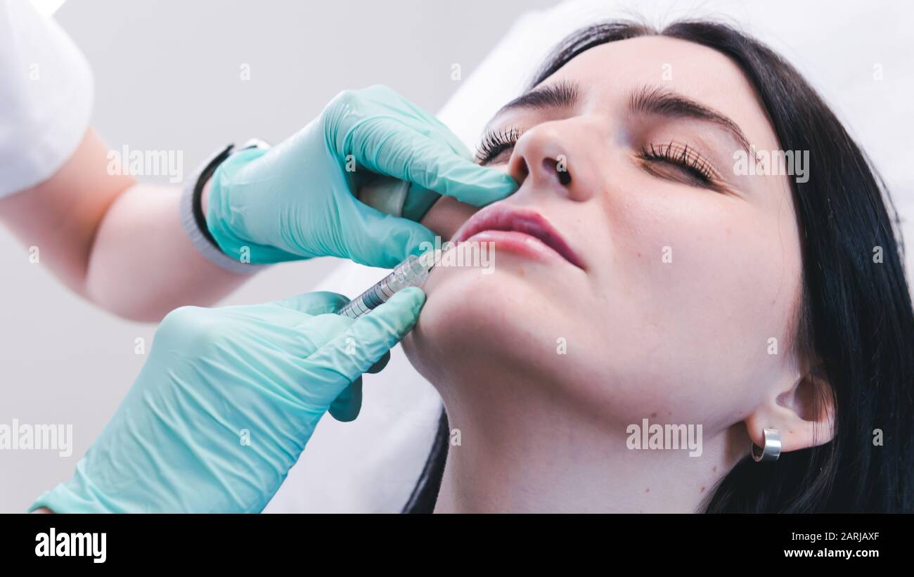 Beautician hands making botox injection in female lips. The doctor ...