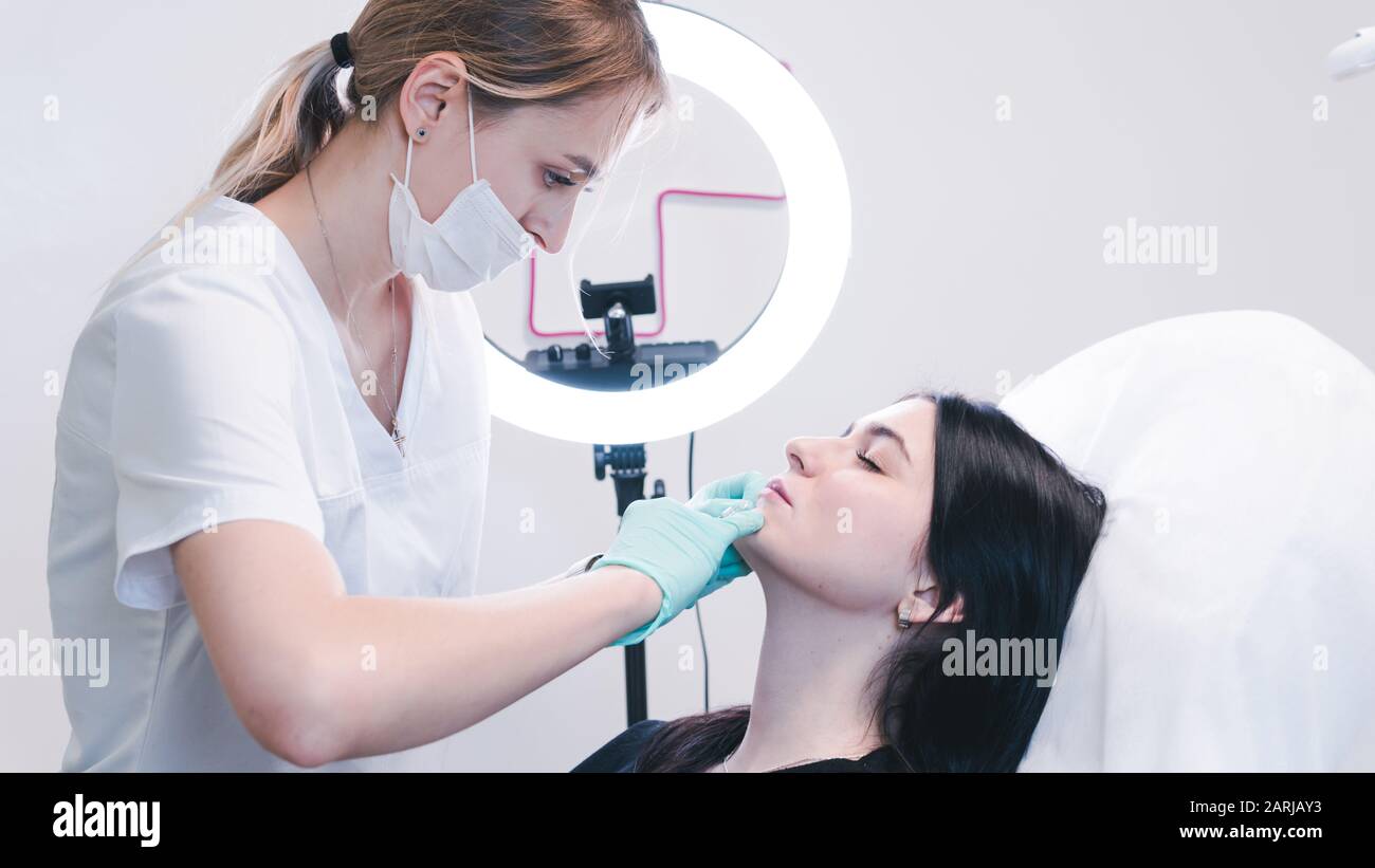 Beautician hands making botox injection in female lips. The doctor ...
