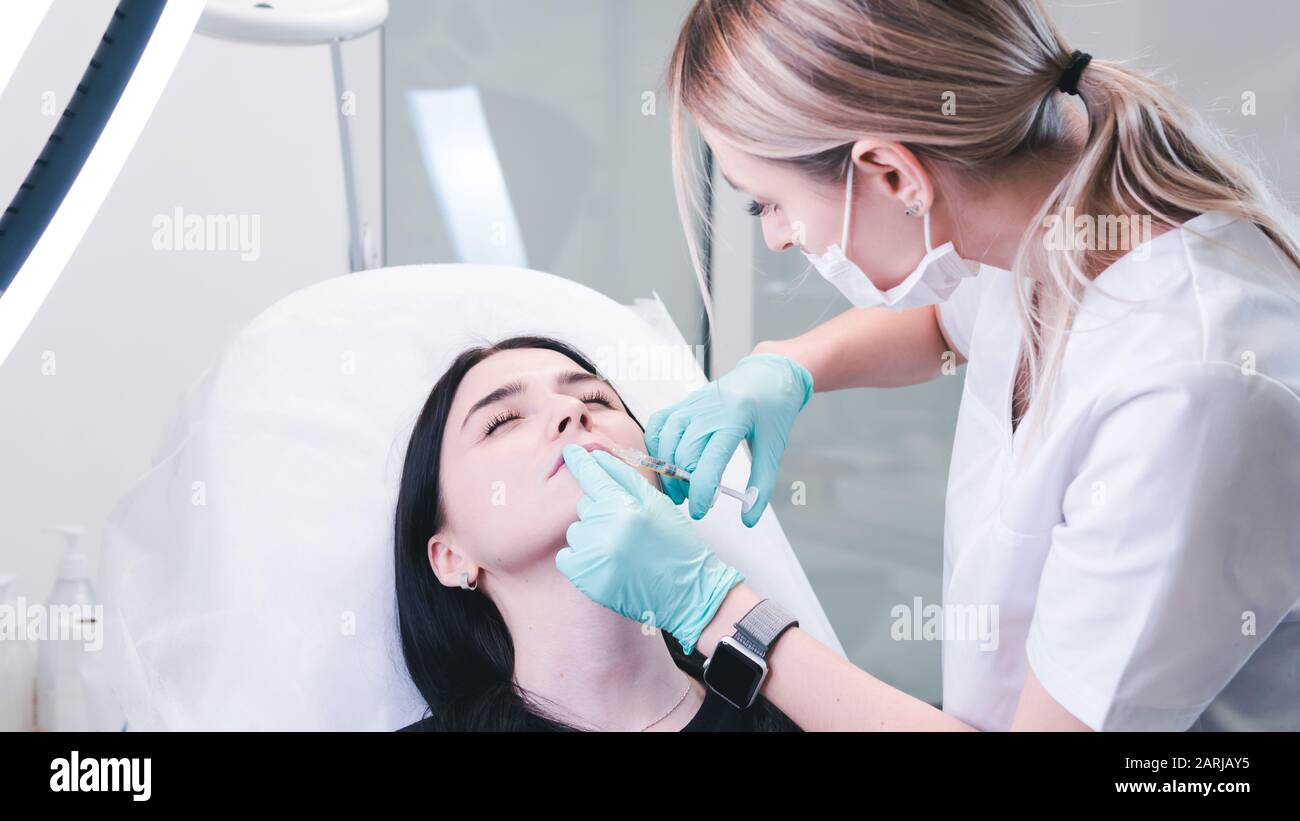 Beautician hands making botox injection in female lips. The doctor ...